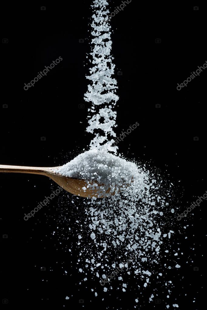 Cristales de sal comestibles cayendo en la cuchara de madera en el ...