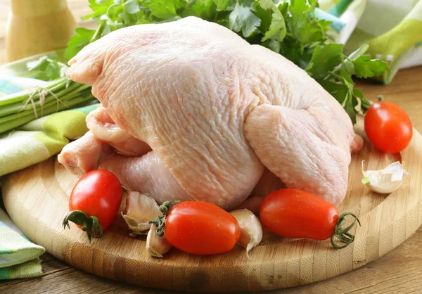 Fresh raw chicken on a cutting board with vegetables and herbs - Stock ...