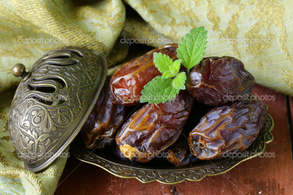 Los dátiles dulces secos en la escudilla a la mesa de madera 2023