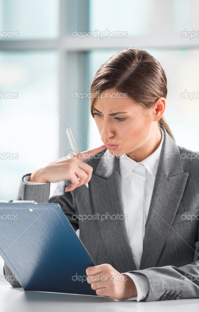 Front view of business woman looking over papers on clipboard at ...