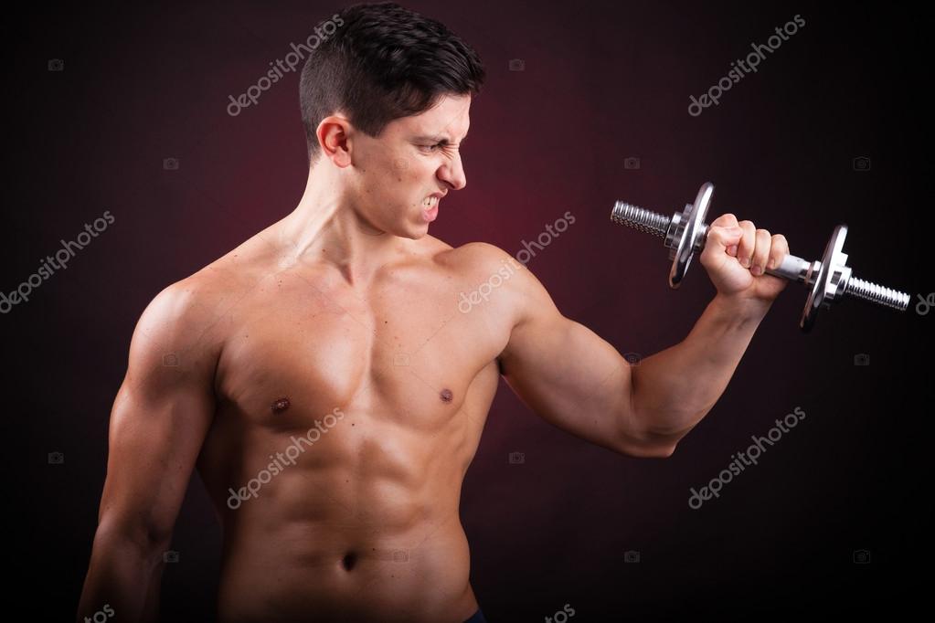 Muscular young man lifting weights on black background Stock Photo by ...