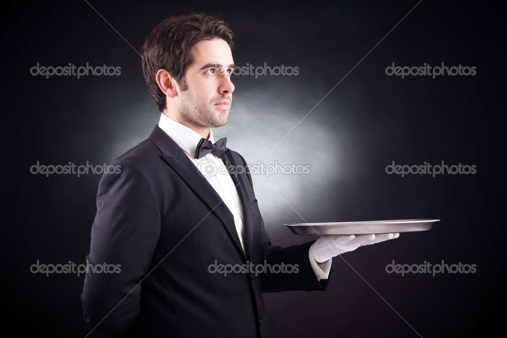 Portrait of a young waiter holding an empty dish on black backgr Stock ...