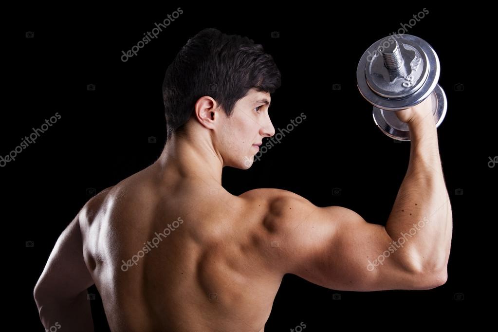Portrait of a strong man lifting weights against a dark background ...