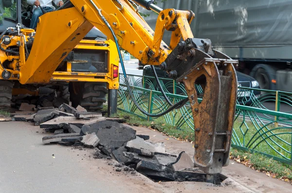 road construction machine with the breaker dividing the asphalt - Stock ...