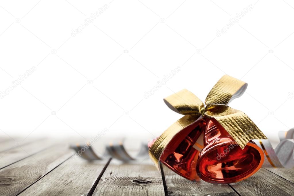 Red bells with a golden bow on wooden planks over white background ...