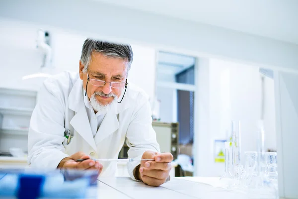 Senior male researcher carrying out scientific research in a lab ...