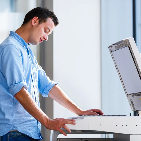 Handsome young man using a copy machine Stock Photo by ©lightpoet 18535167
