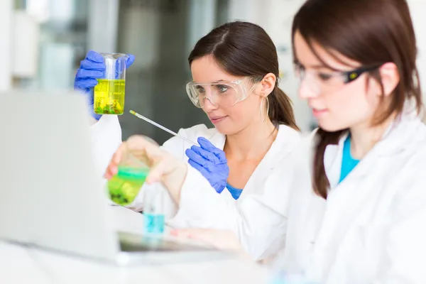 Two young female researchers carrying out experiments in a lab Stock ...