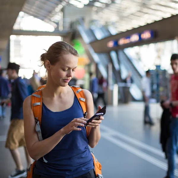 Woman in a train station, sending message - Stock Image - Everypixel
