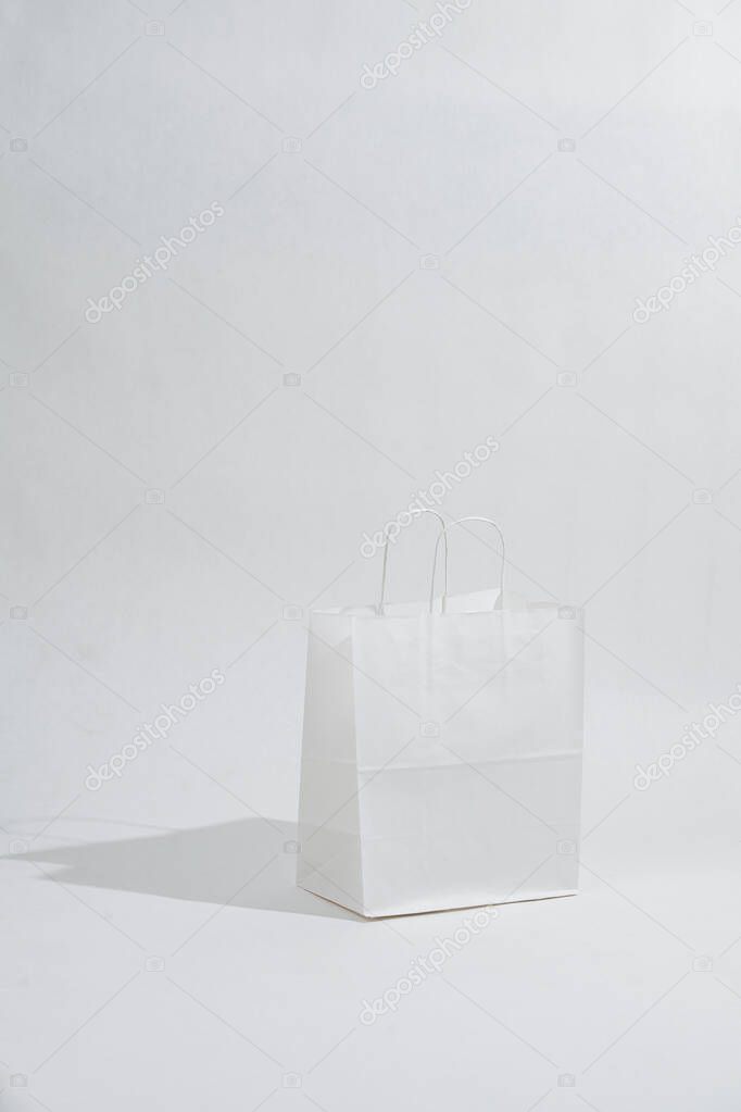 White empty paper bag with rope handles casting a shadow over white ...