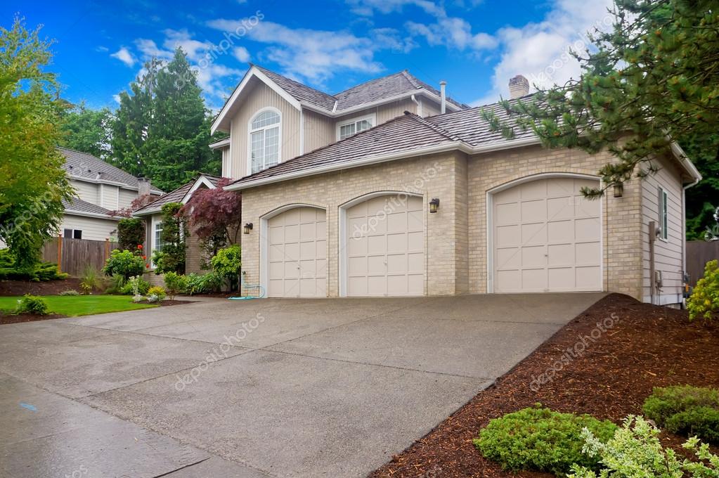 Large beige house with three car garage and large driveway. — Stock ...
