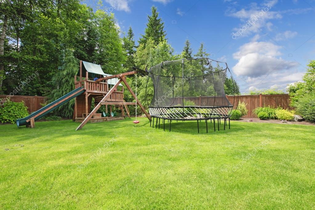 Play kinds ground area with tremplin in fenced backyard. Stock Photo by ...