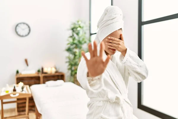 Young brunette woman wearing towel and bathrobe standing at beauty ...