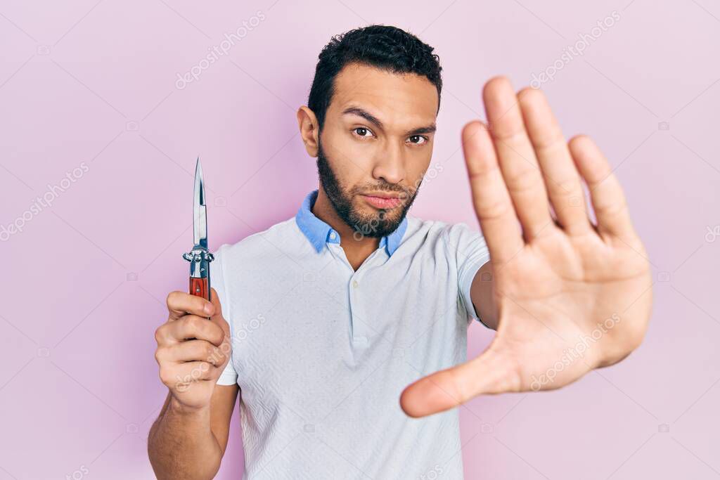 Hombre hispano con barba sosteniendo navaja con mano abierta haciendo ...