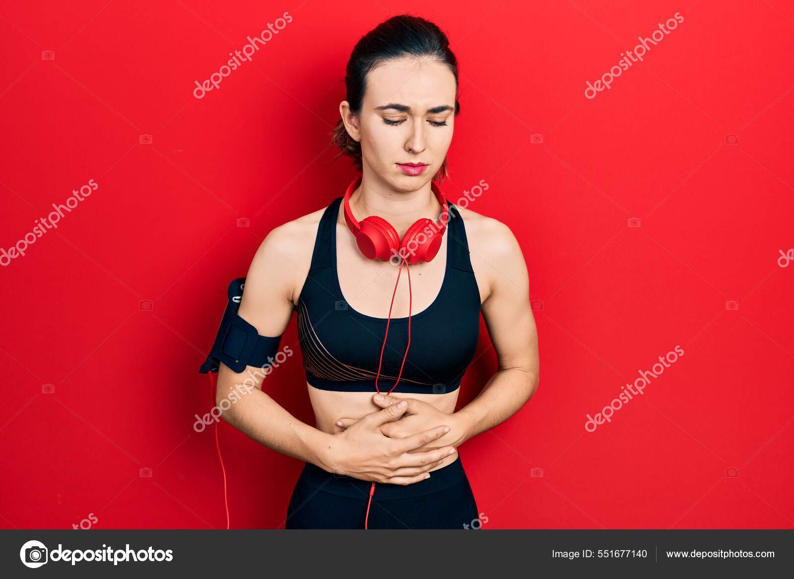 Young Hispanic Girl Wearing Gym Clothes Using Headphones Hand Stomach ...