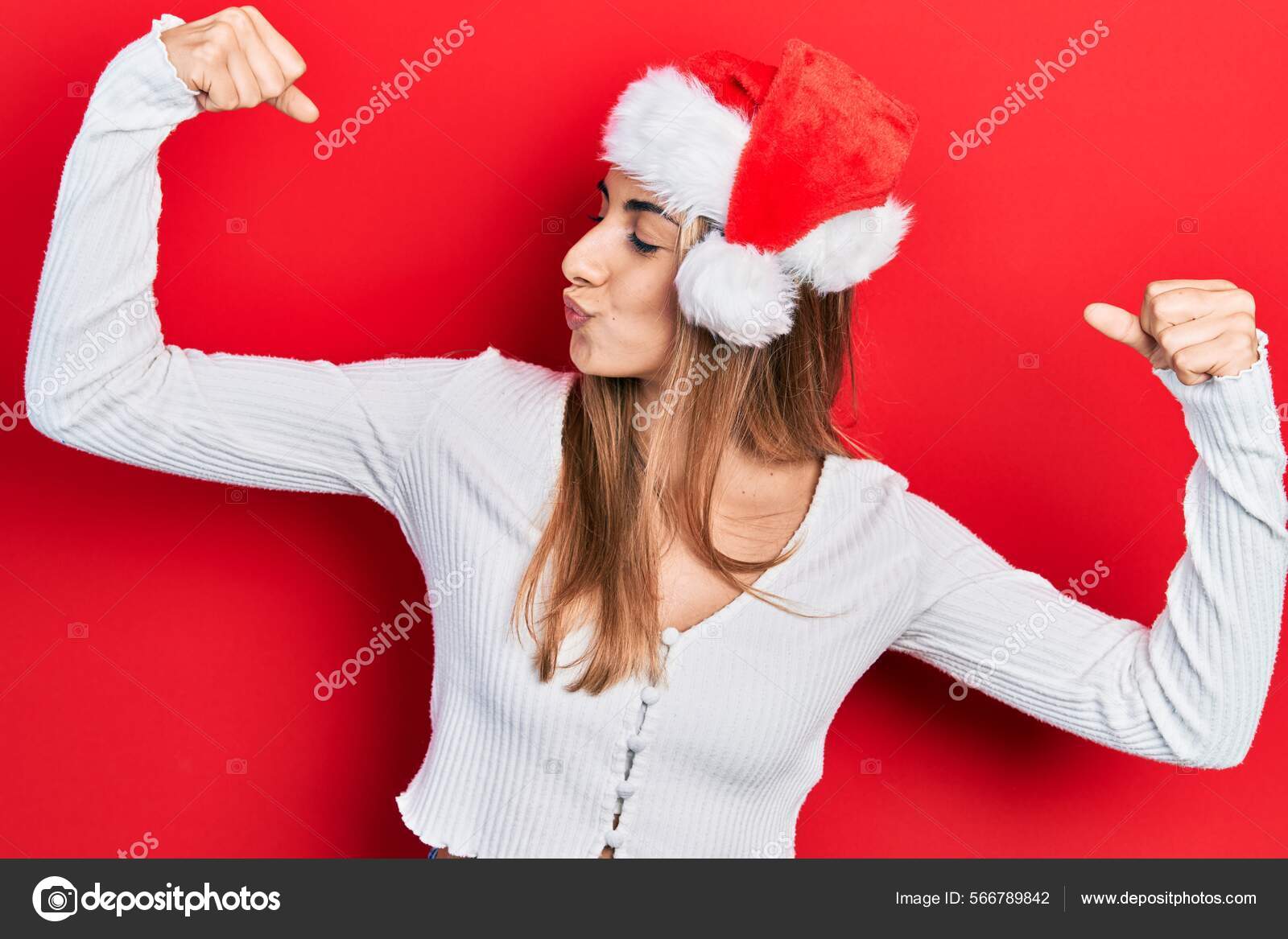 Beautiful Hispanic Woman Wearing Christmas Hat Showing Arms Muscles