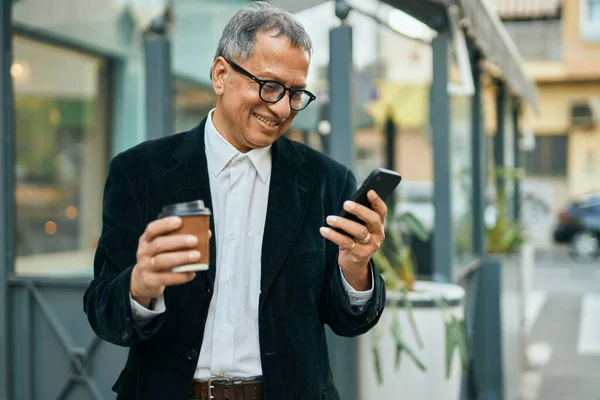 Middle age southeast asian man smiling using smartphone and drinking a ...