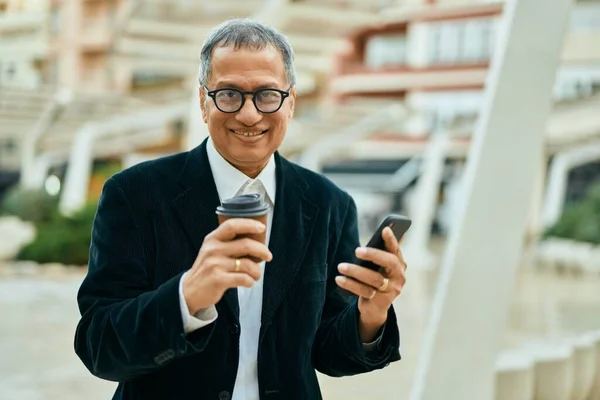 Middle age southeast asian man smiling using smartphone and drinking a ...