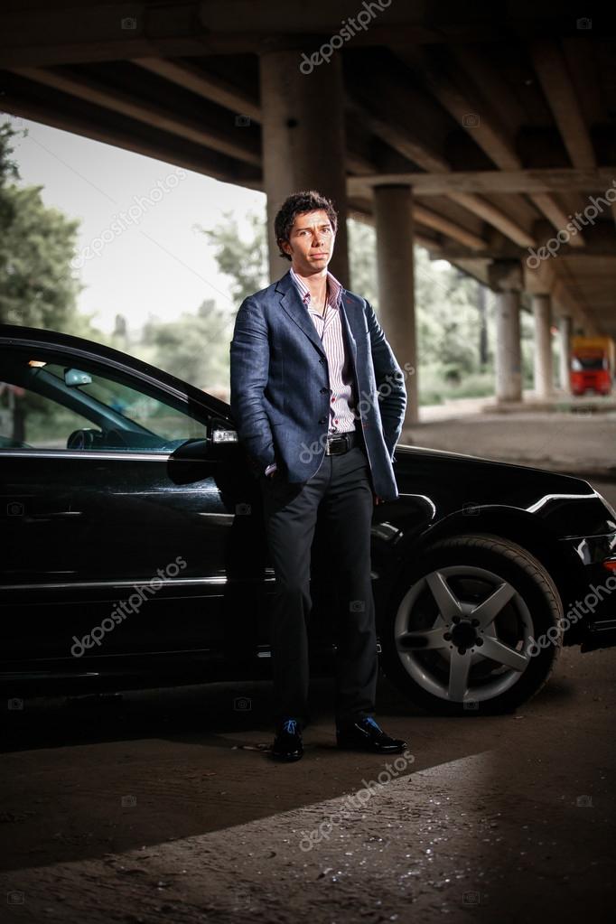 Elegant man in suit posing against black luxury car Stock Photo by ...