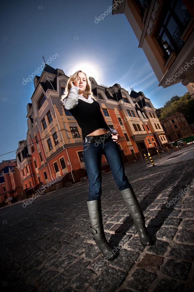Woman in boots standing on pavement against old buildings Stock Photo ...