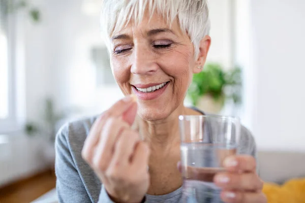 Smiling happy healthy middle aged 50s woman holding glass of water ...