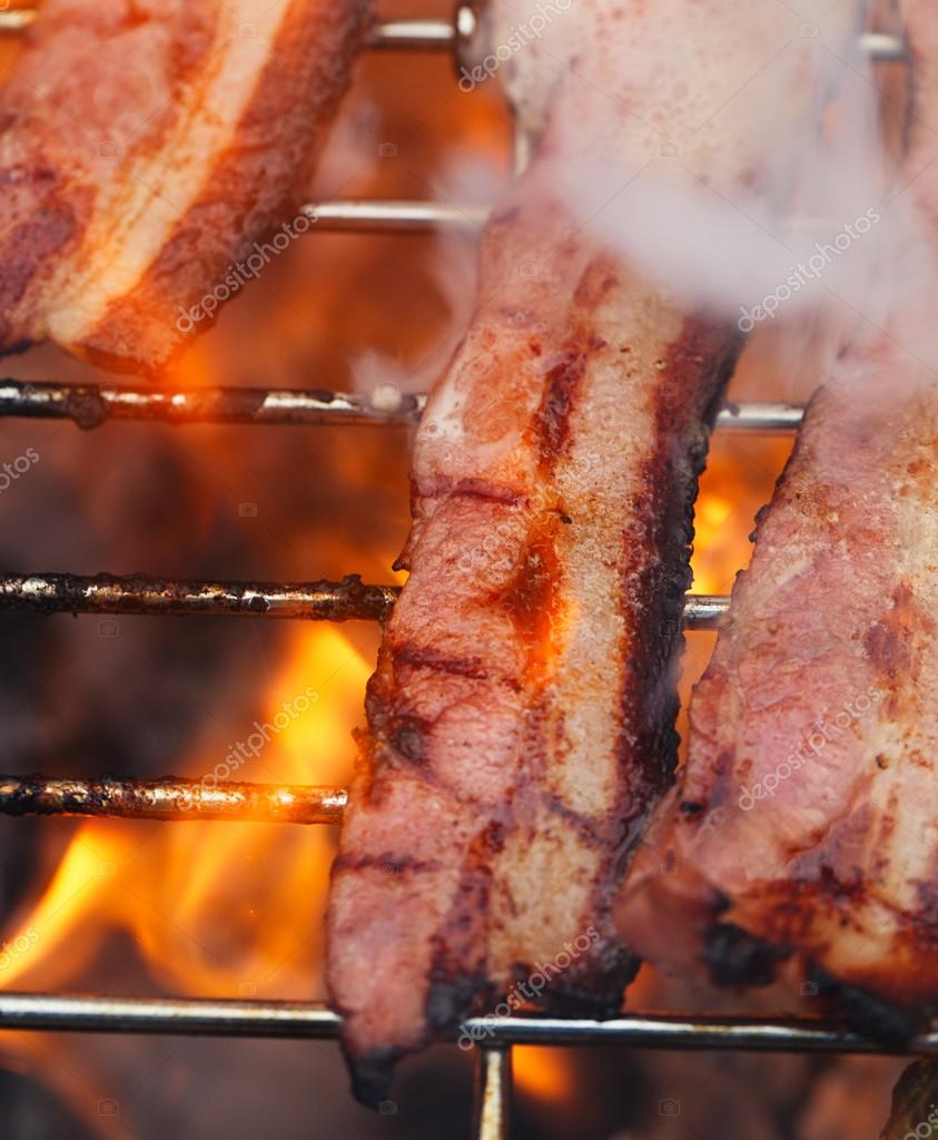 Bacon meat on bbq barbecue grill with fire — Stock Photo © lvenks #25218995