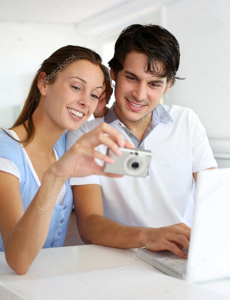 Couple at home uploading photographies on internet — Stock Photo © Goodluz #13964911
