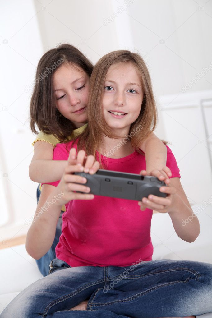 Young girls playing with gaming console on sofa — Stock Photo © Goodluz ...