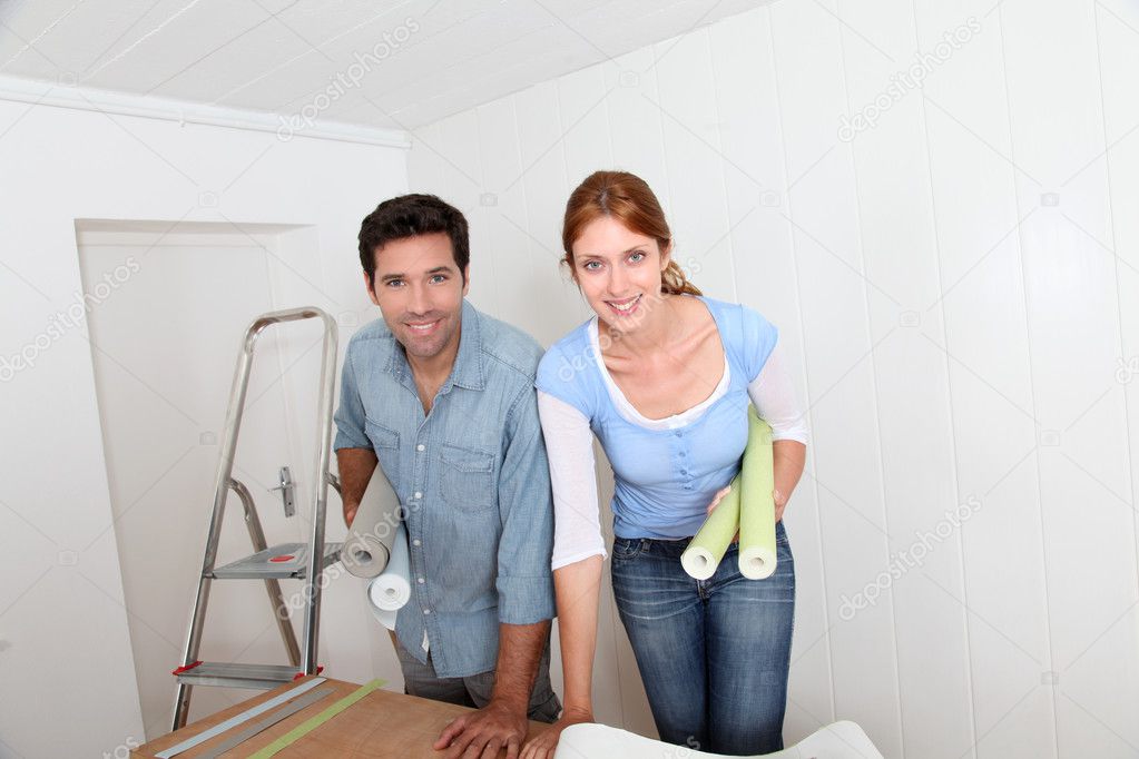Couple putting new wallpaper in room — Stock Photo © Goodluz #18218311