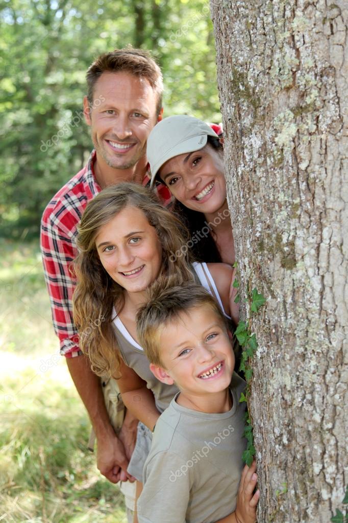 Smiling family standing behind a tree Stock Photo by ©Goodluz 18263485