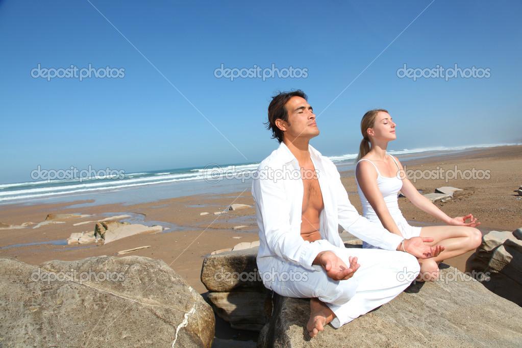 Couple doing yoga exercises on the beach — Stock Photo © Goodluz #18274013