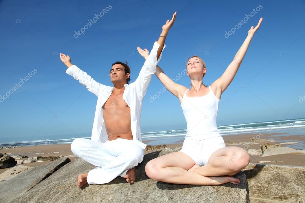 Couple doing yoga exercises on the beach — Stock Photo © Goodluz #18274039