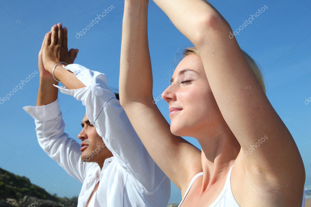 Couple doing yoga exercises on the beach — Stock Photo © Goodluz #18274083