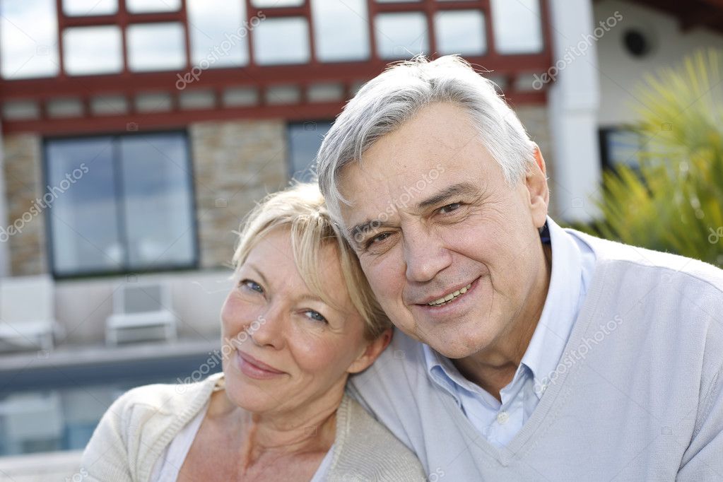 Sonriente pareja de ancianos de pie en el jardín del hogar 2024