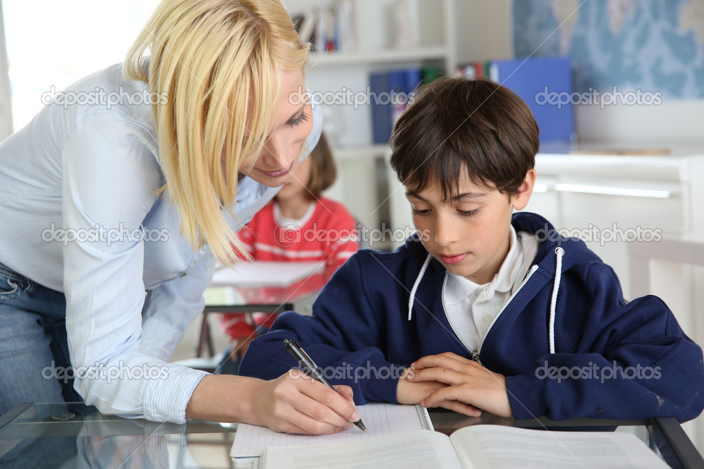 Teacher helping young boy with lesson — Stock Photo © Goodluz #27880115