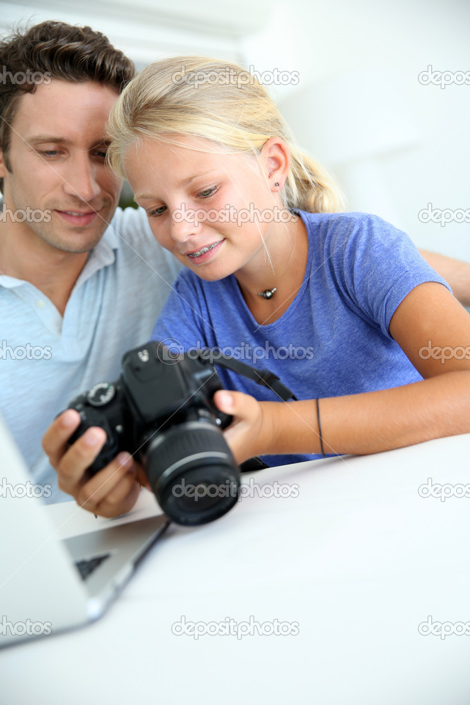 Father and daughter looking at digital camera and laptop — Stock Photo ...