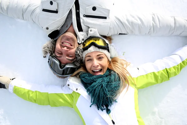 Cheerful couple laying down in snow - Stock Image - Everypixel