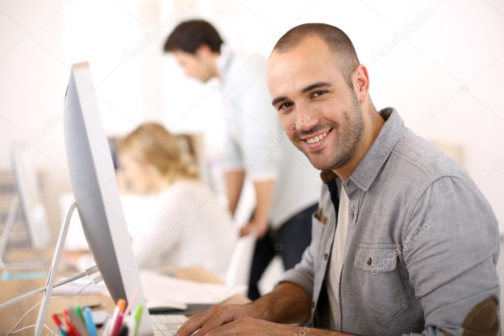 Guy sitting in front of desktop computer — Stock Photo © Goodluz #35314107