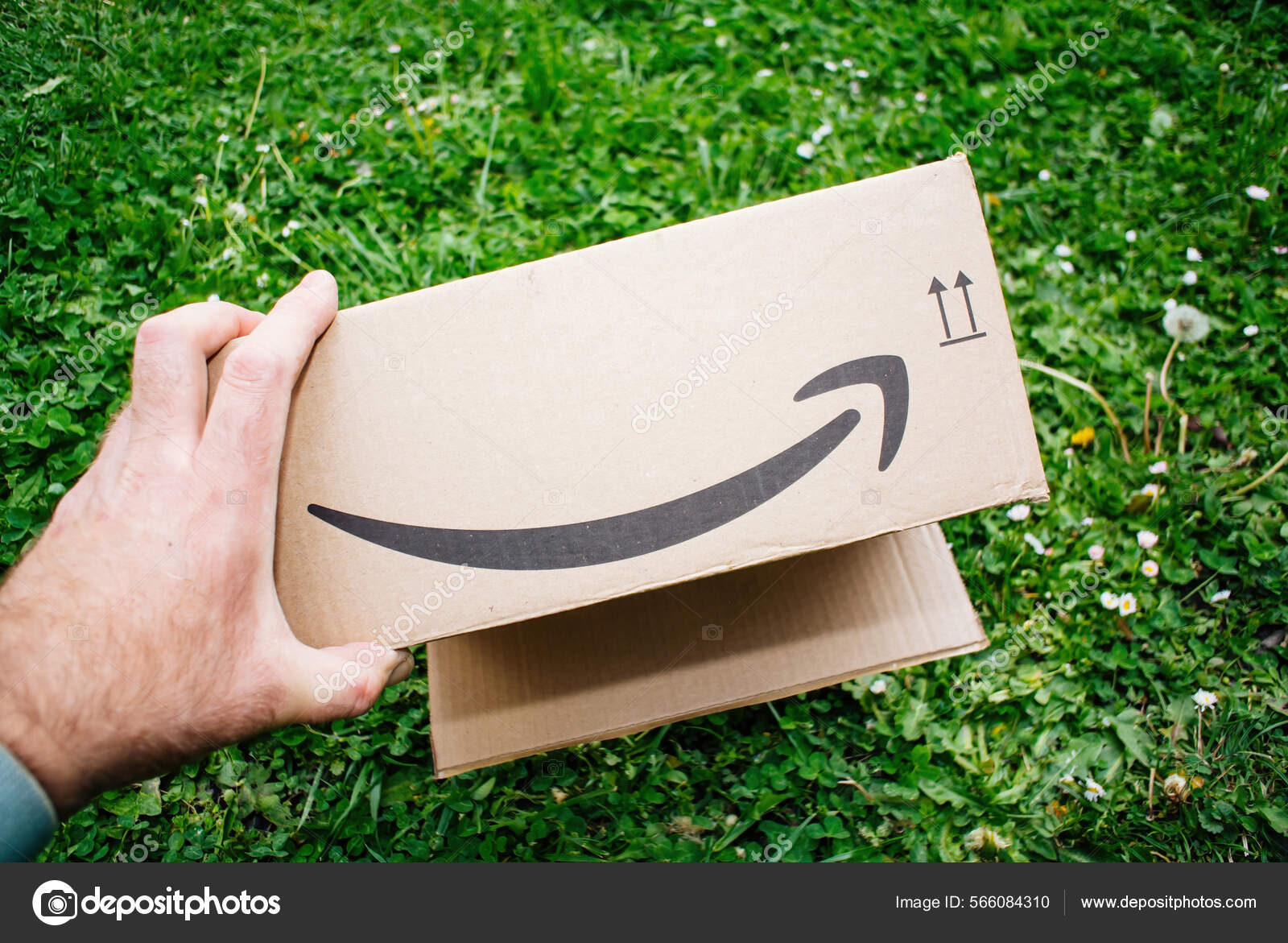 POV male hand holding Amazon cardboard box with smiling arrow logotype ...