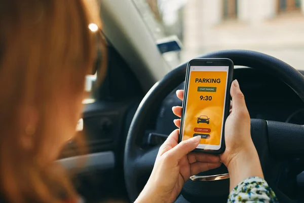 Woman using mobile parking app on smartphone. Driver using smartphone to pay for parking. Car ...