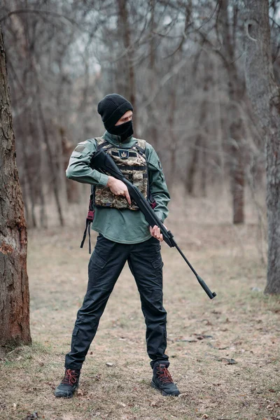 Young man stands with pump gun in his hands weared in body armor and ...