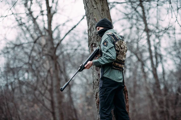 Young man stands with pump gun in his hands weared in body armor and ...