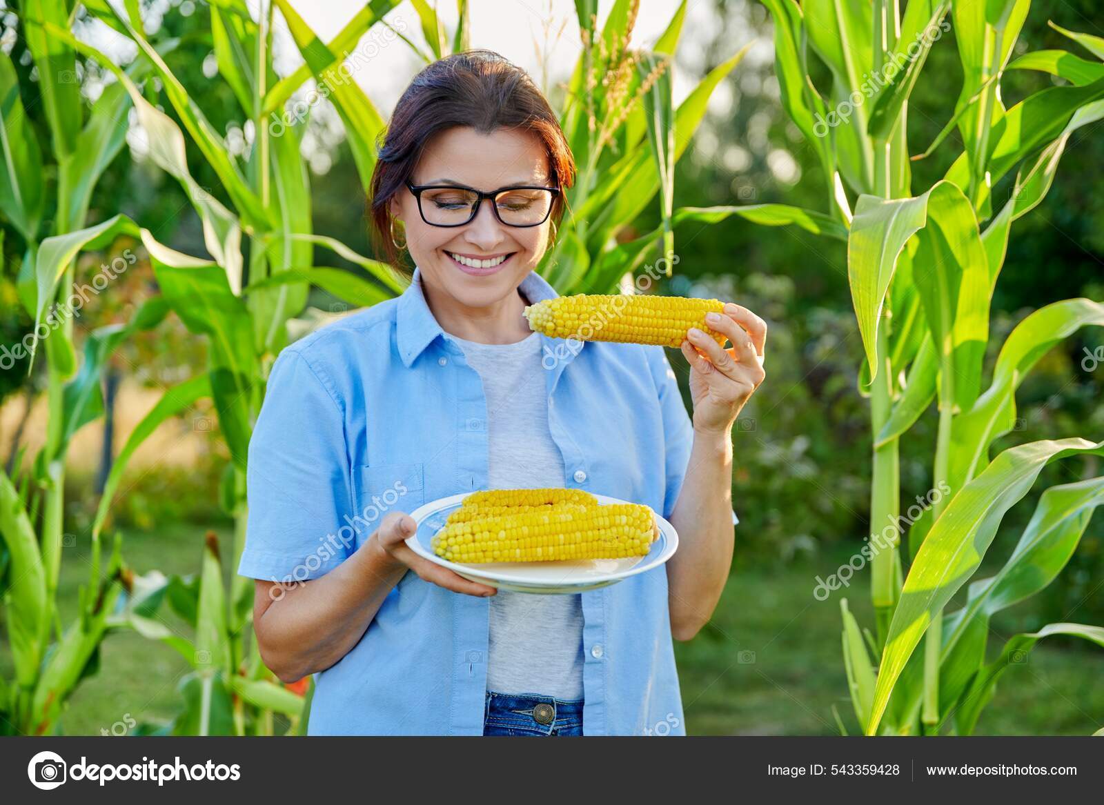 Smiling middle aged woman eating boiled ripe corn on the cob — Stock ...