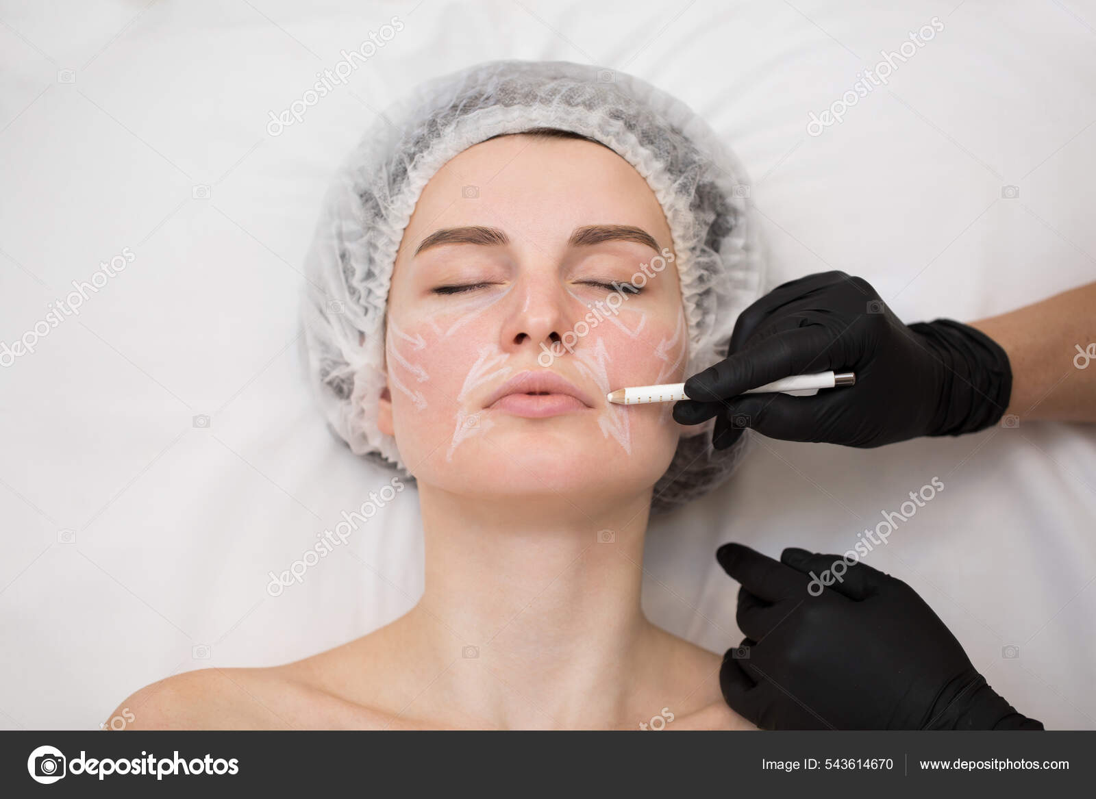Beautician draws the contours of a white pencil on the face of the ...