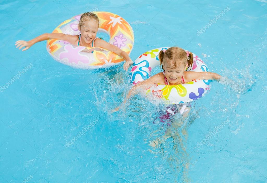 Two happy little girls splashing around in the pool Stock Photo by ...