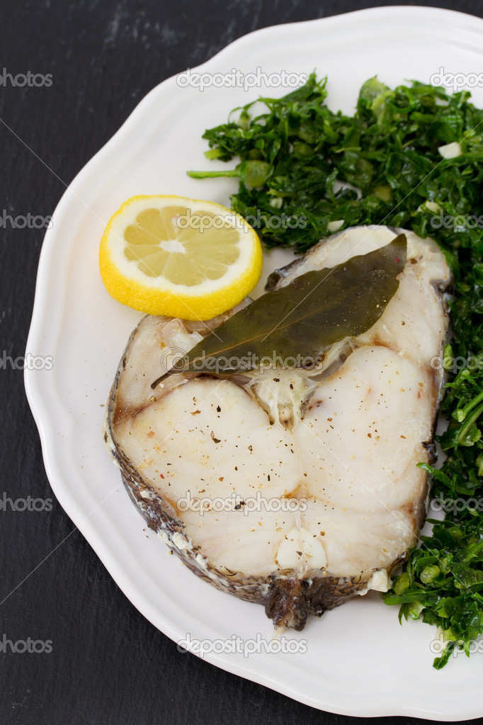Pescado cocido con limón y col en plato blanco 2022