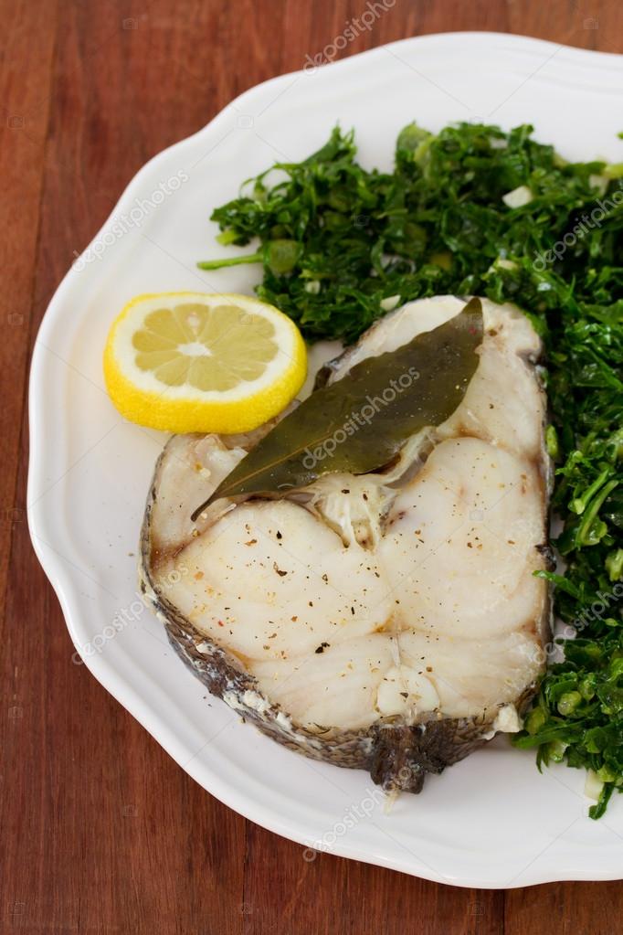 Pescado cocido con limón y col en plato blanco 2022
