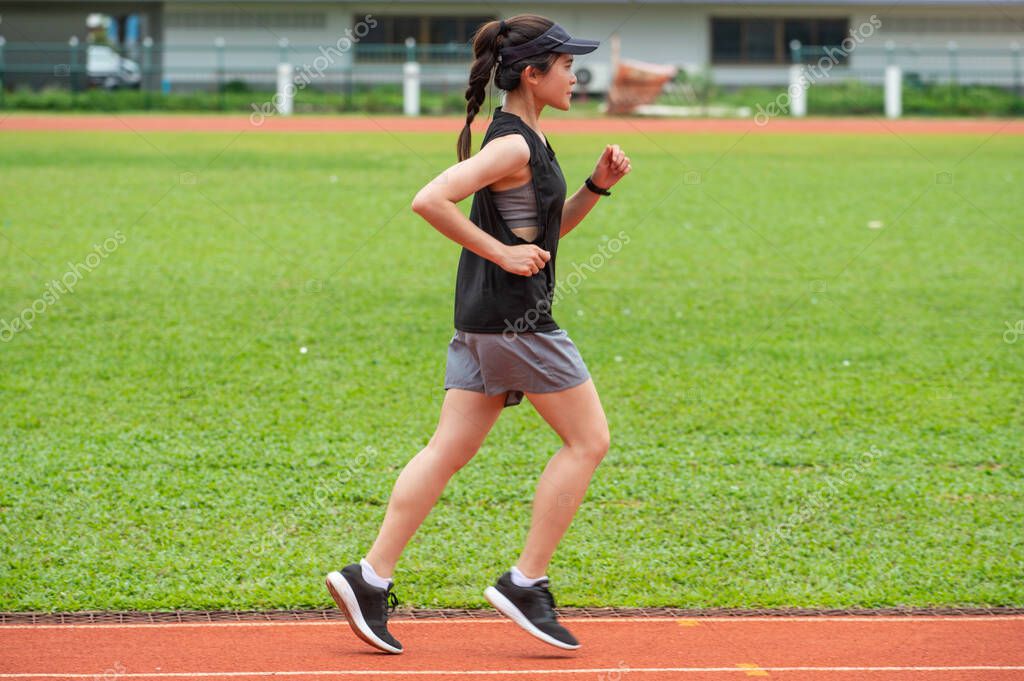 Vista lateral de la joven atleta corredora corriendo en la pista de ...