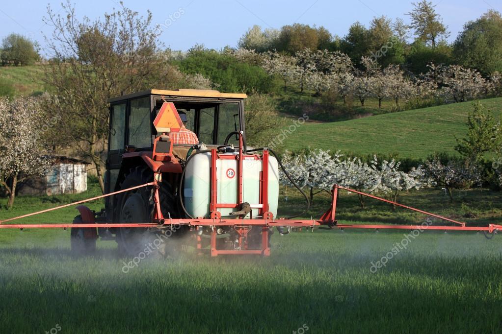 Farm tractor spraying field before planting Stock Photo by ...