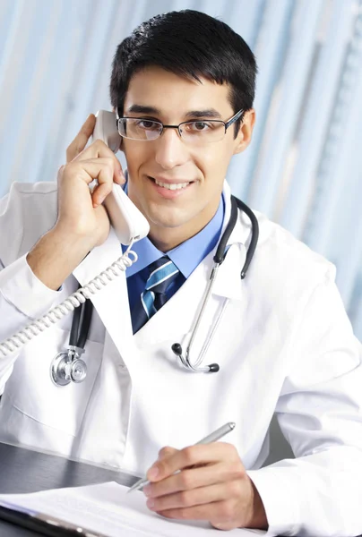 Young doctor on phone, at office - Stock Image - Everypixel